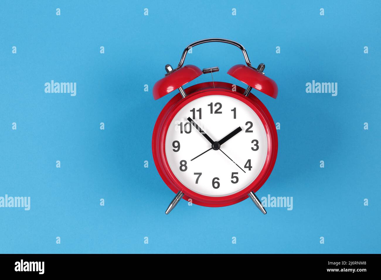 Retro red clock on a blue background Stock Photo - Alamy