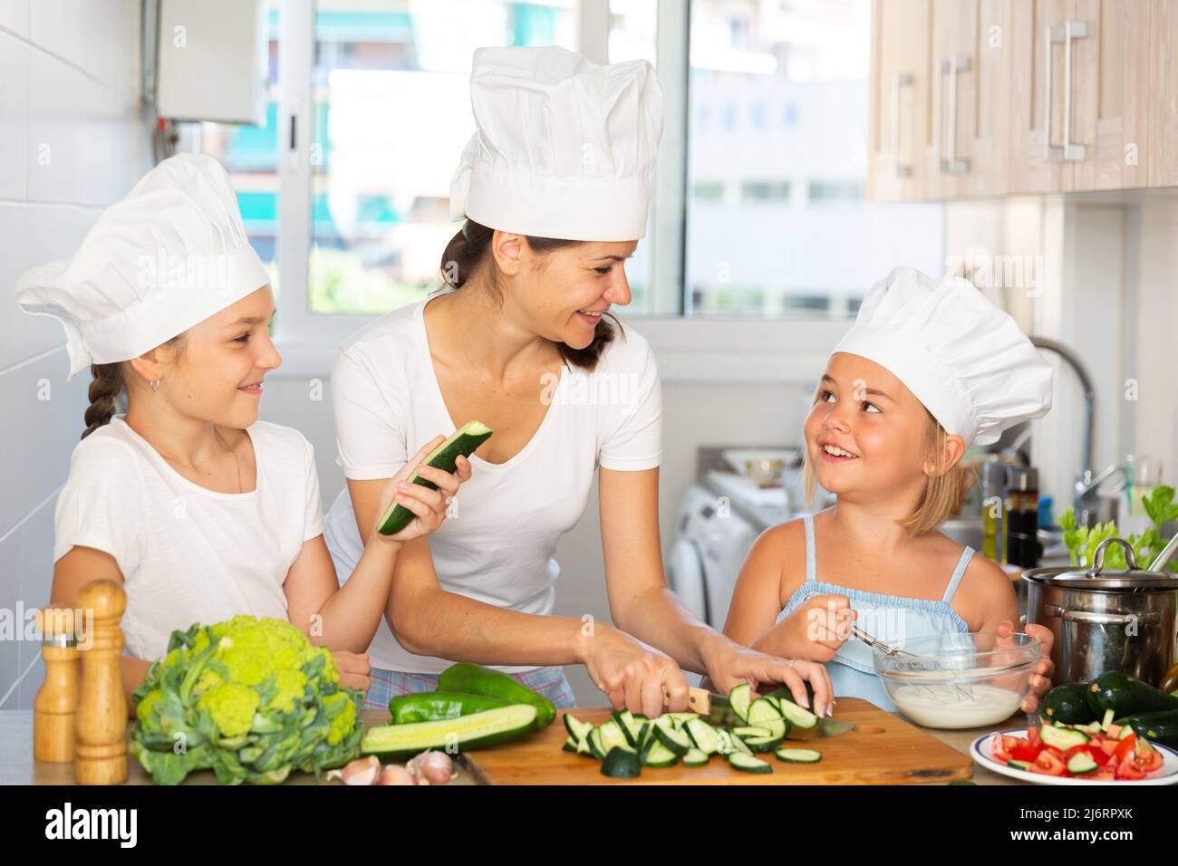 Young woman and two girls cooking together Stock Photo - Alamy
