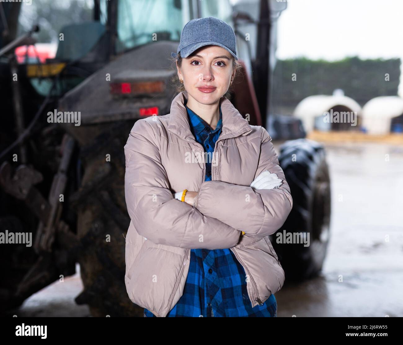 Confident smiling young woman farmer standing near tractor Stock Photo ...
