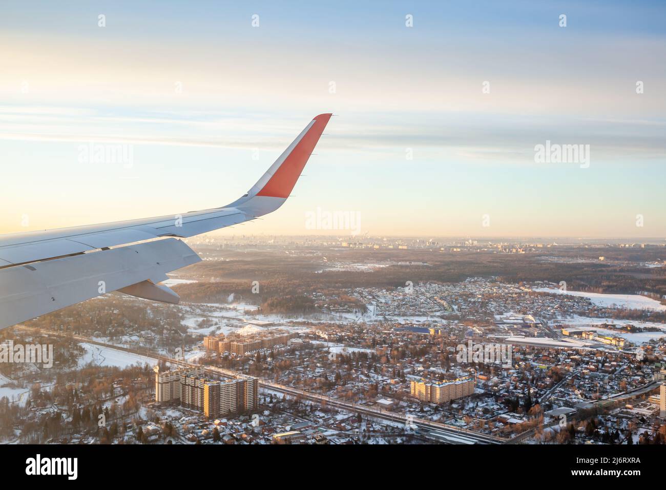 Airplane flight at sunset or dawn. Aircraft's wing and land seen ...