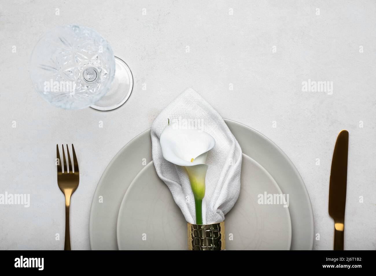 Beautiful table setting with calla lily and glass on light background ...