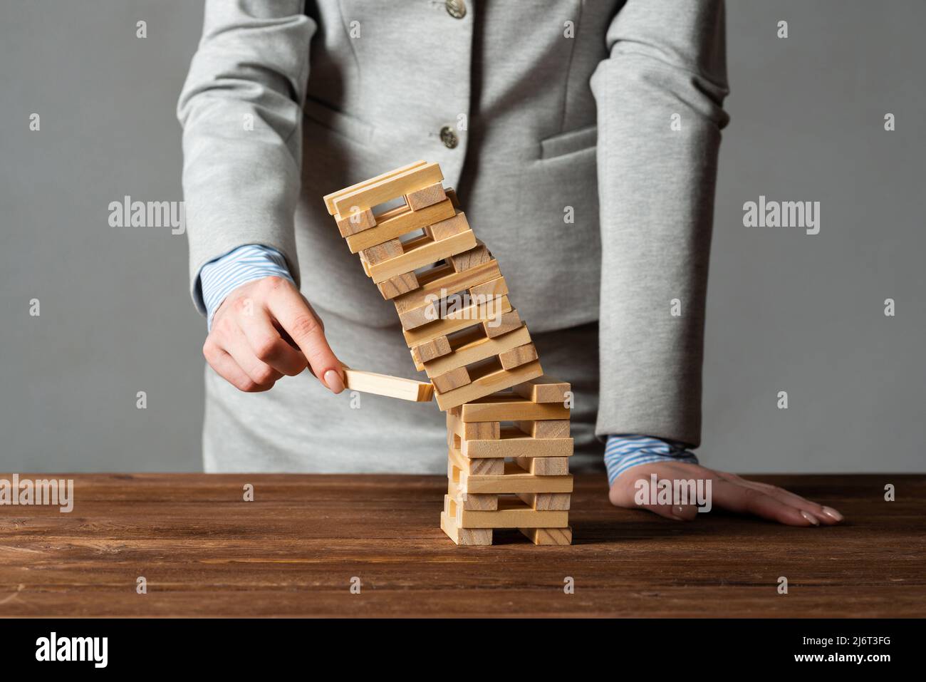 Businesswoman removing wooden block from tower Stock Photo - Alamy