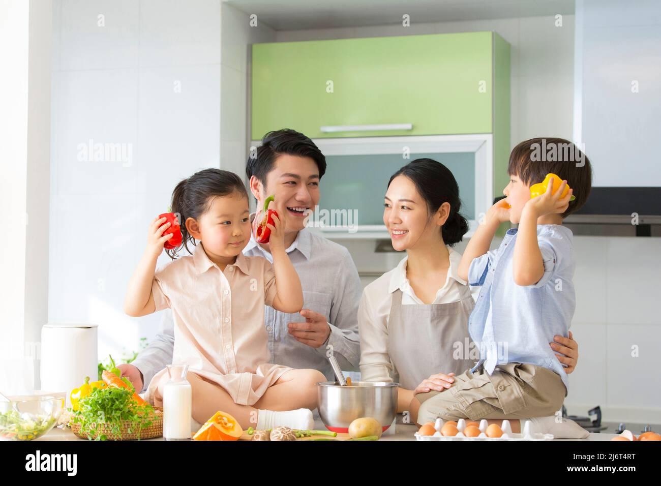 Family kitchen parentage. Young parents are teaching two preschoolers ...