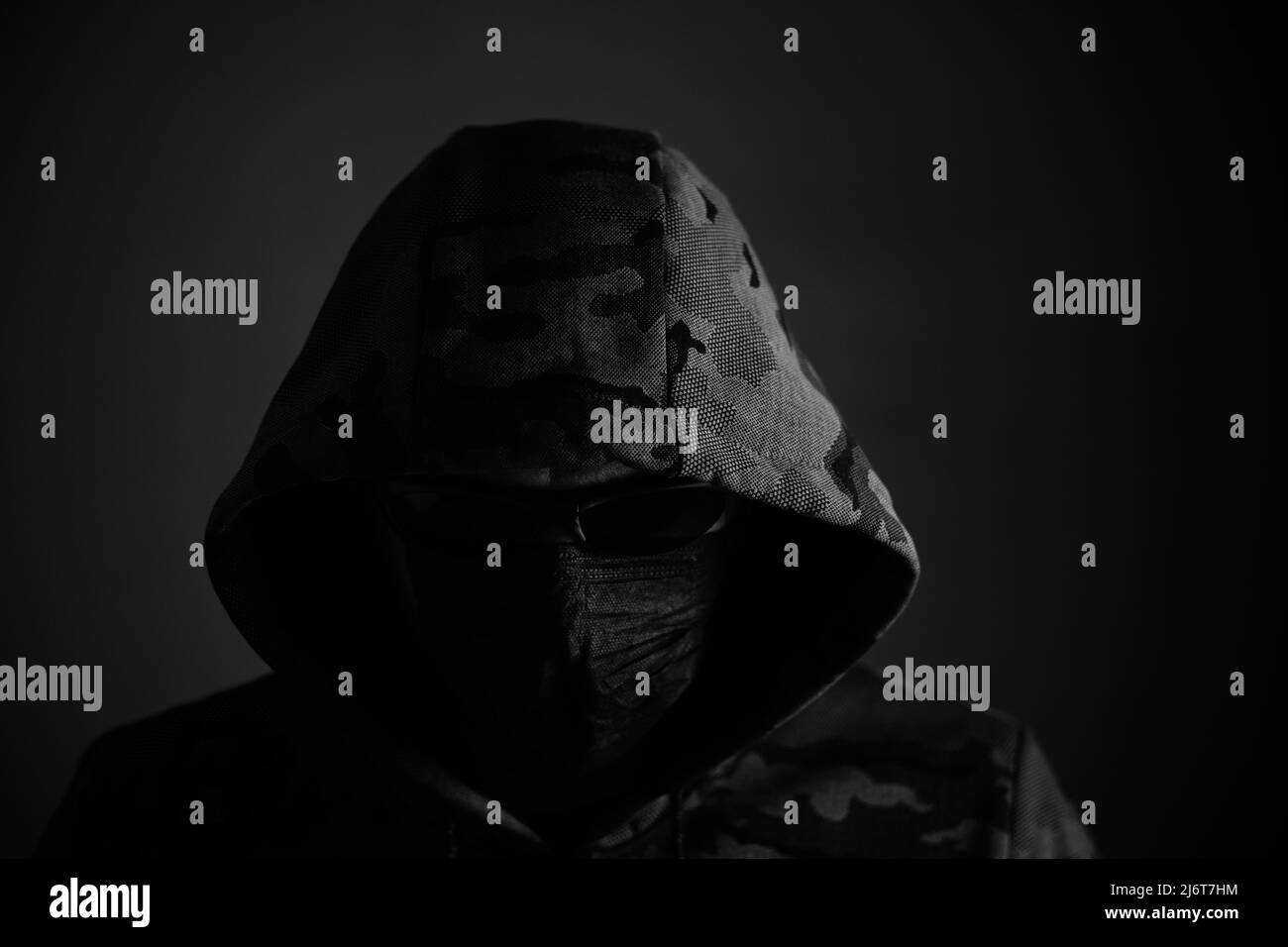 Stylish man in dark hoodie with black glasses and mask dark background ...
