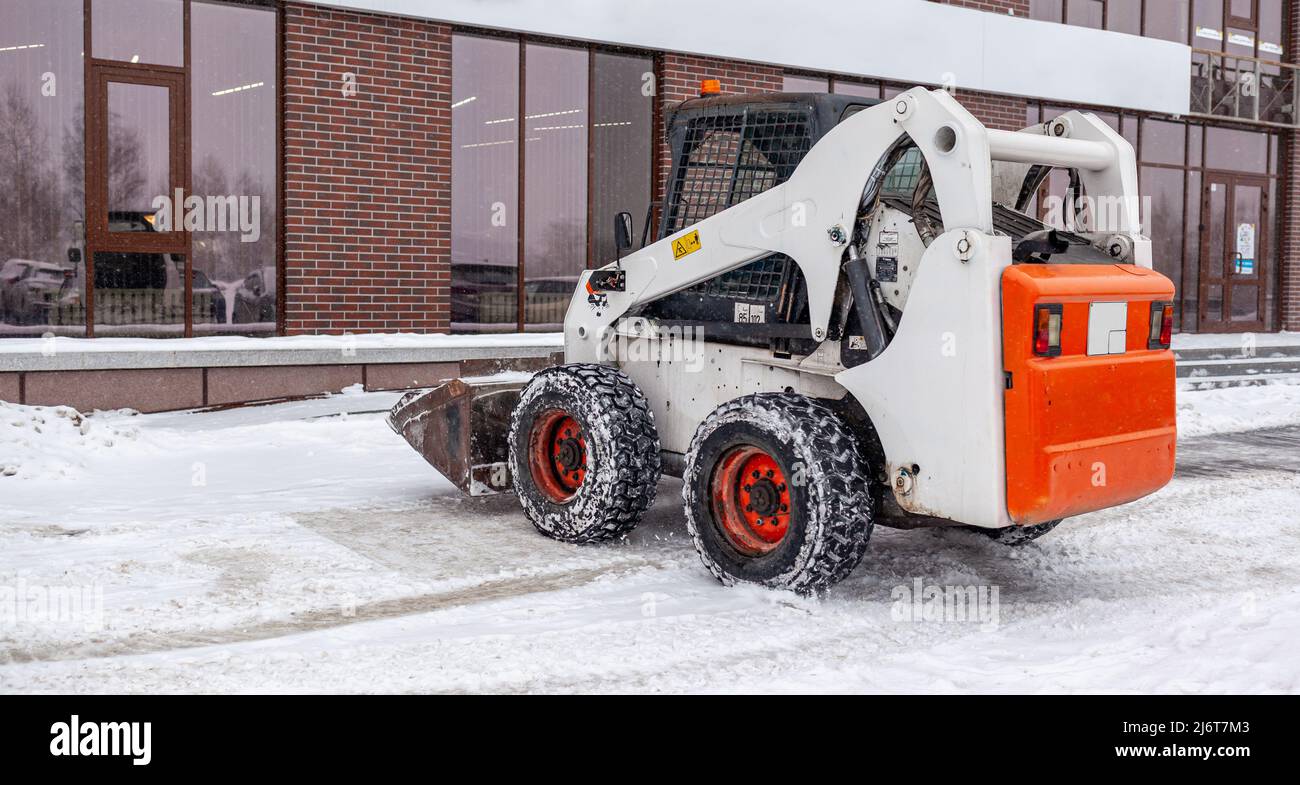 Small snow removal vehicle removing snow on city square. Yellow or ...