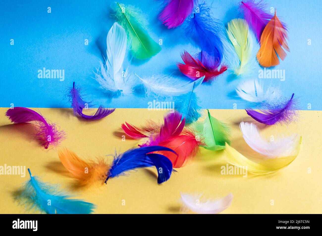 Flying colorful feathers with yellow background flag Stock Photo - Alamy