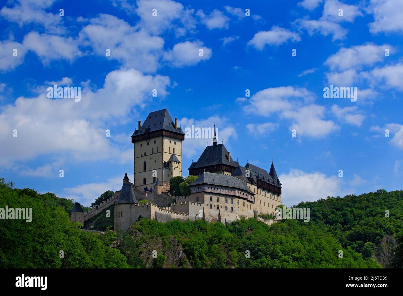 Gothic royal castle Karlstejn in green forest during summer with blue ...