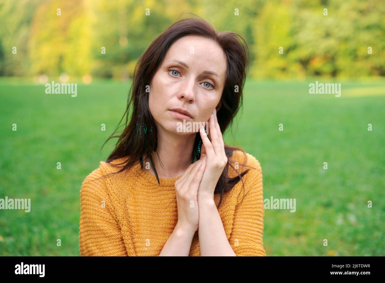 Portrait caucasian woman with sensitive face in park against background ...