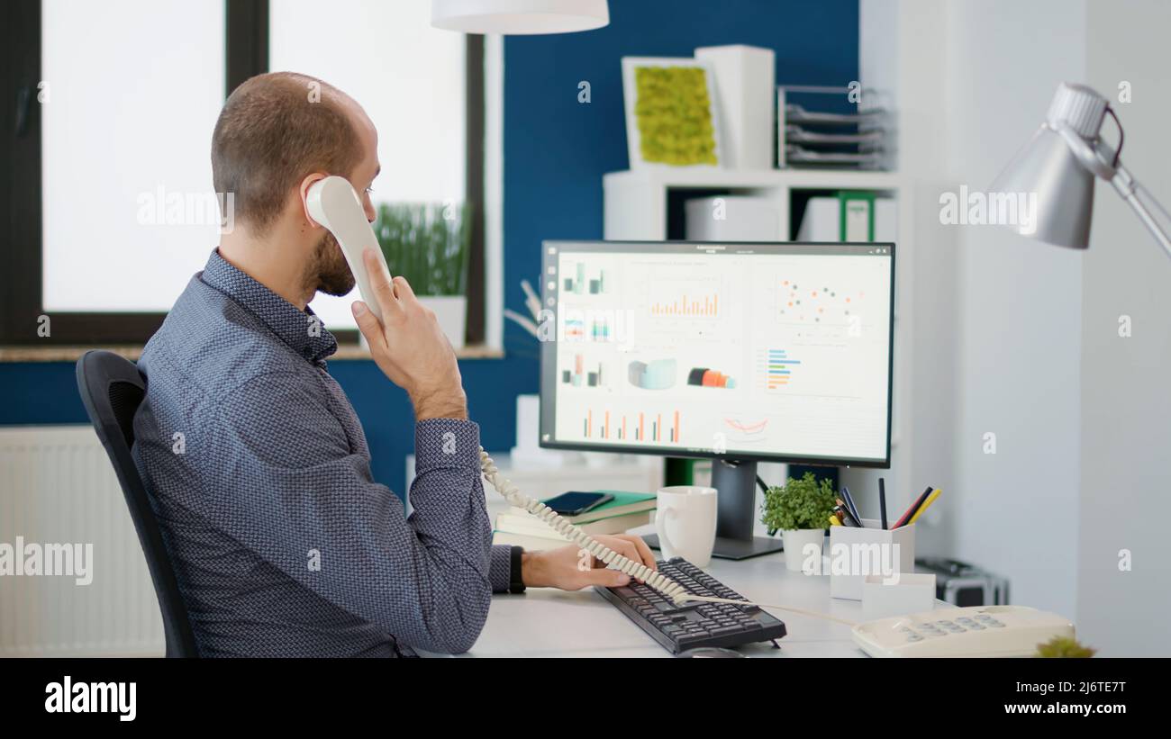 Company secretary talking on landline phone call at desk, working on ...