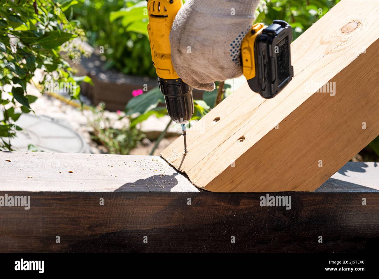 A carpenter works with a yellow electric screwdriver, twists a screw ...
