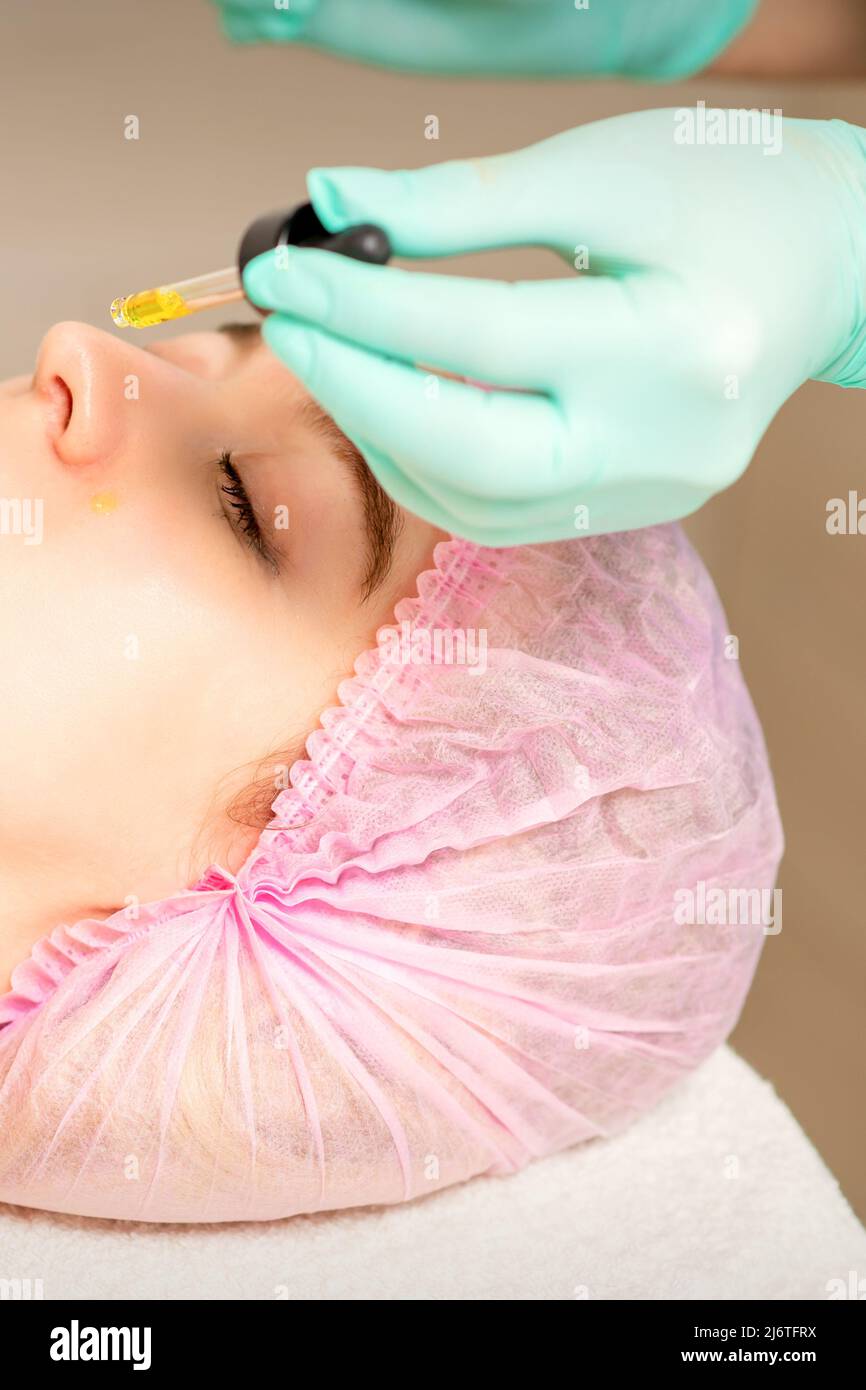 Young white woman getting acid organic retinol peel face skin with the ...