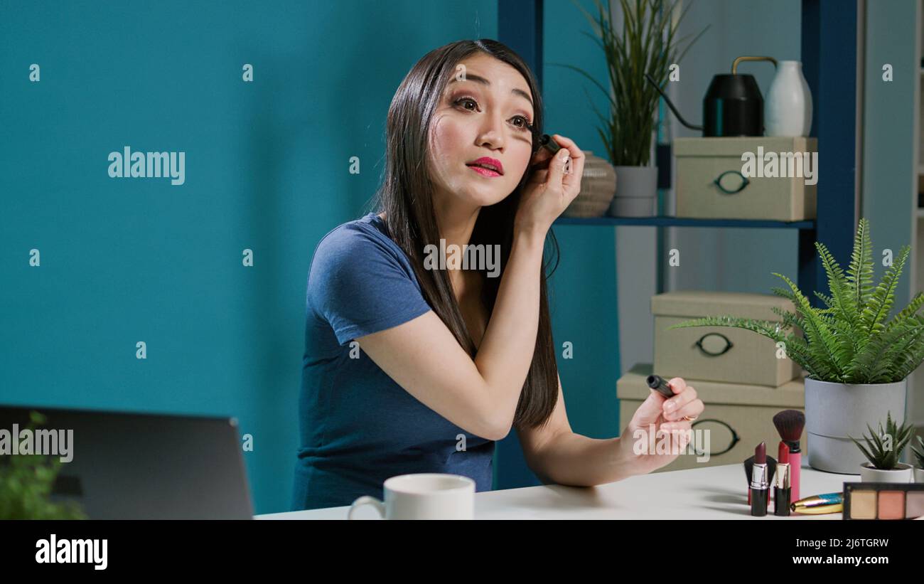 Asian content creator testing mascara product on vlogging camera ...