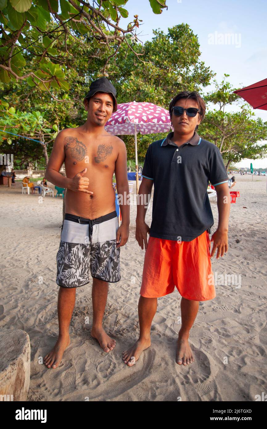 Two Balinese men at the beach in Kuta, Bali, one shirtless with tattoos ...