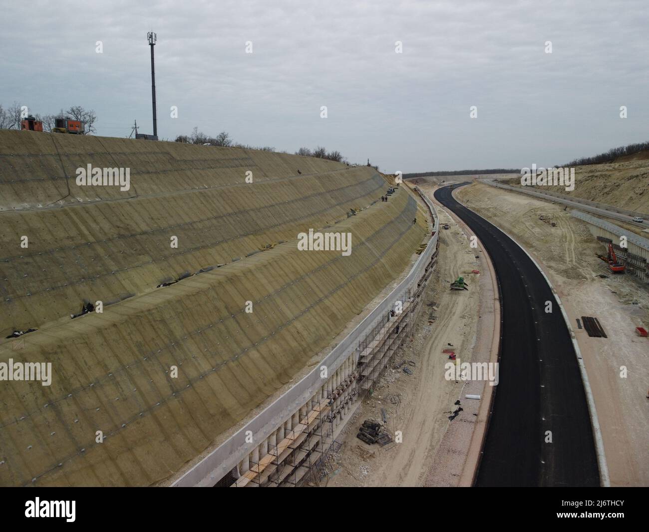 Workers reinforce the slope over the new road. Road construction in ...
