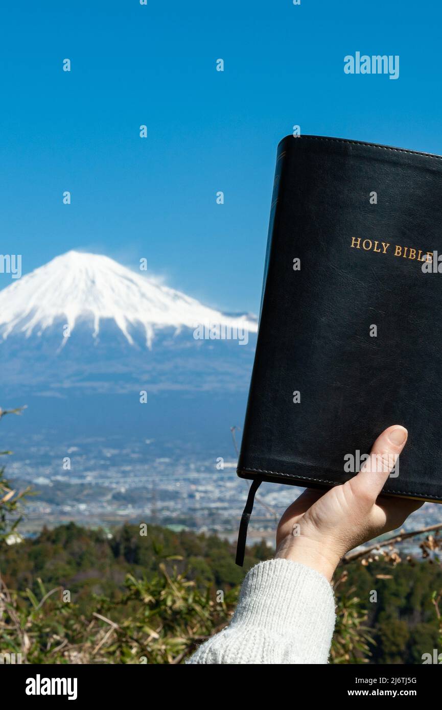 Raised hand holding the Holy Bible in front of Mount Fuji in Japan ...