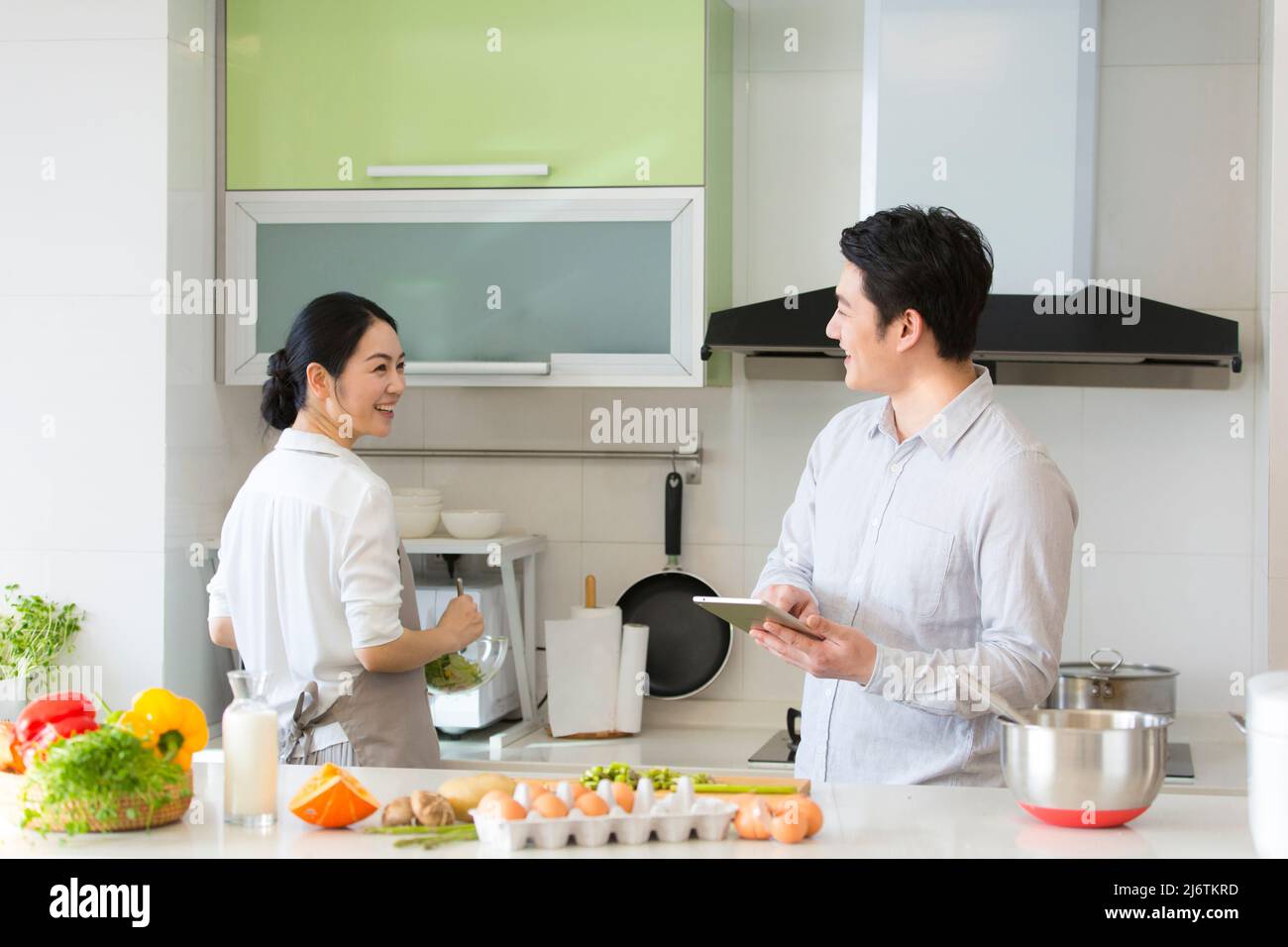 Young couple cooking together in the family kitchen. Husband using ...