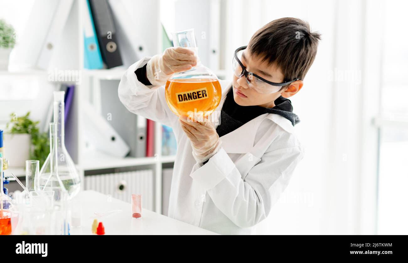 School boy wearing protection glasses doing chemistry experiment in ...