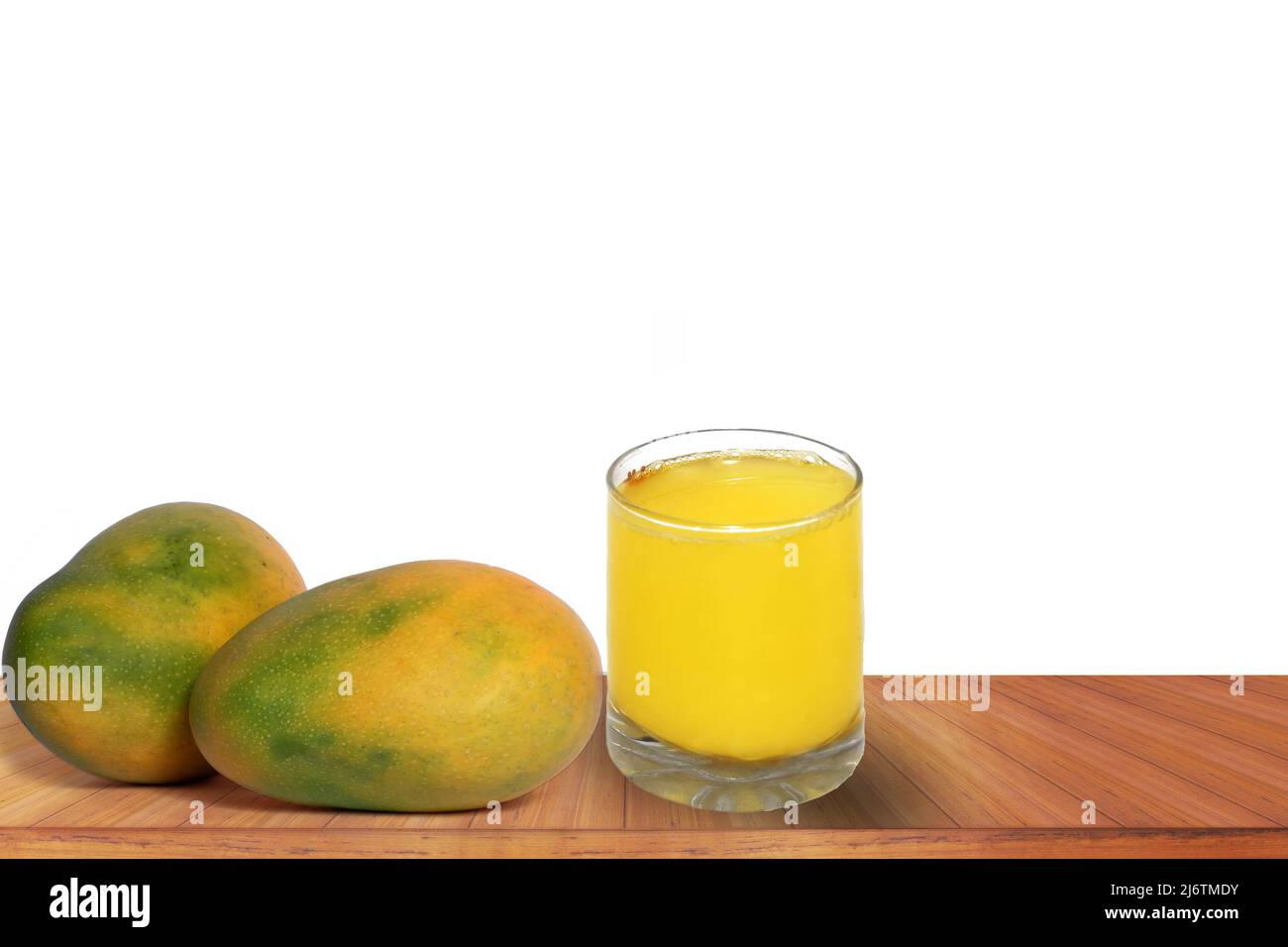 A mango juice in a glass and mangoes on a wooden table on a white ...