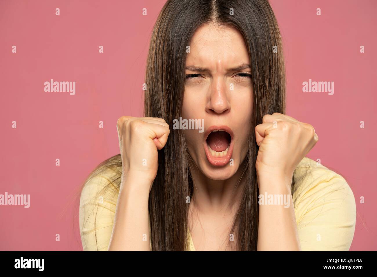 Mad emotional angry woman arguing on you on pink studio background ...