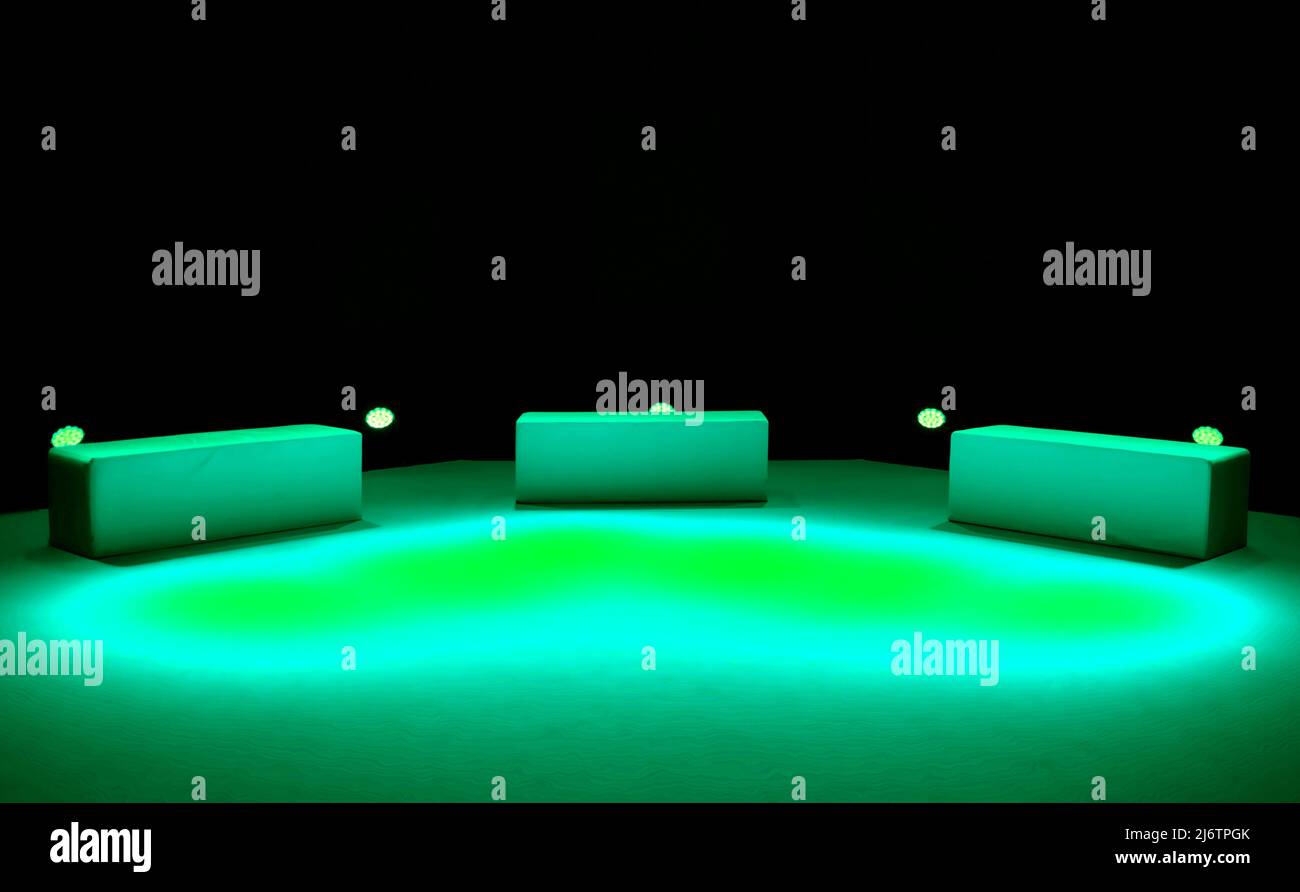 Three seats and green lighting on stage Stock Photo - Alamy