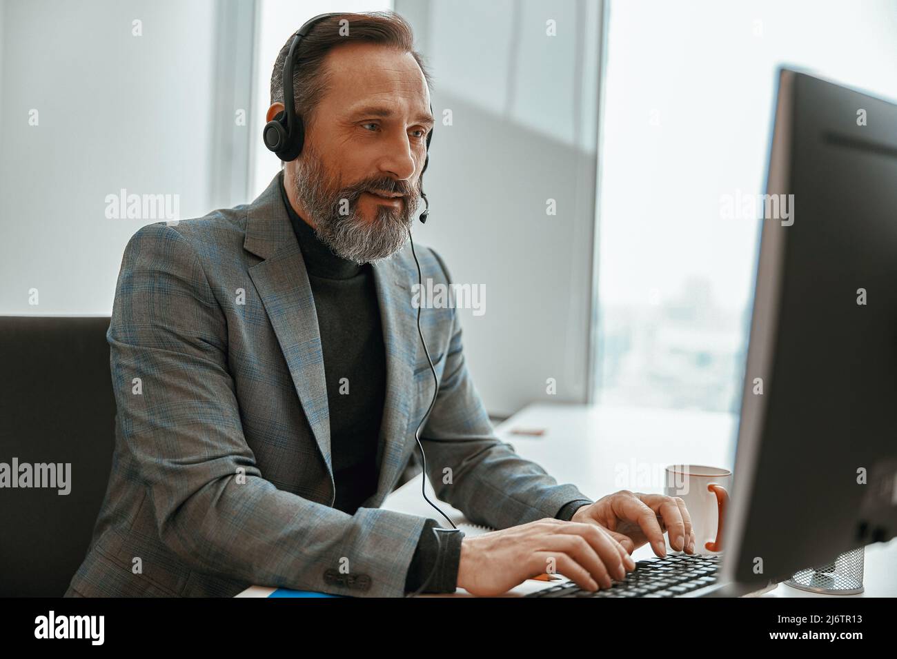 Smiling man is busy while speaking online Stock Photo - Alamy