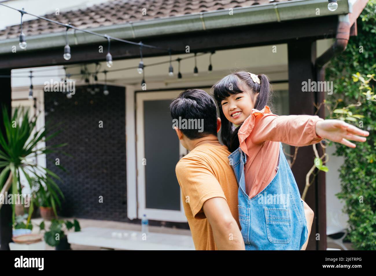Young father giving his daughter piggyback and smiling in front of ...