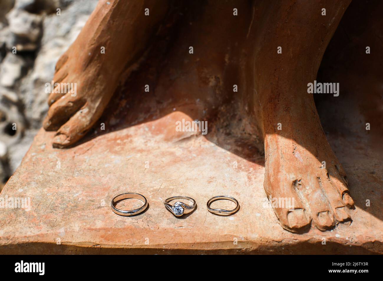 Three wedding ring on a stone statue Stock Photo - Alamy