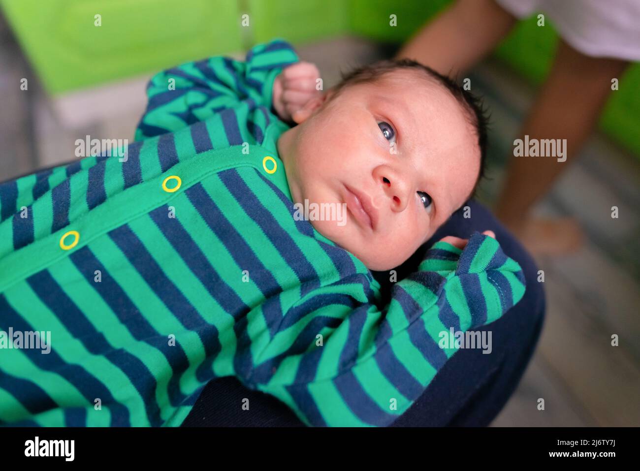 Newborn baby in striped clothes lies with arms raised up Stock Photo ...