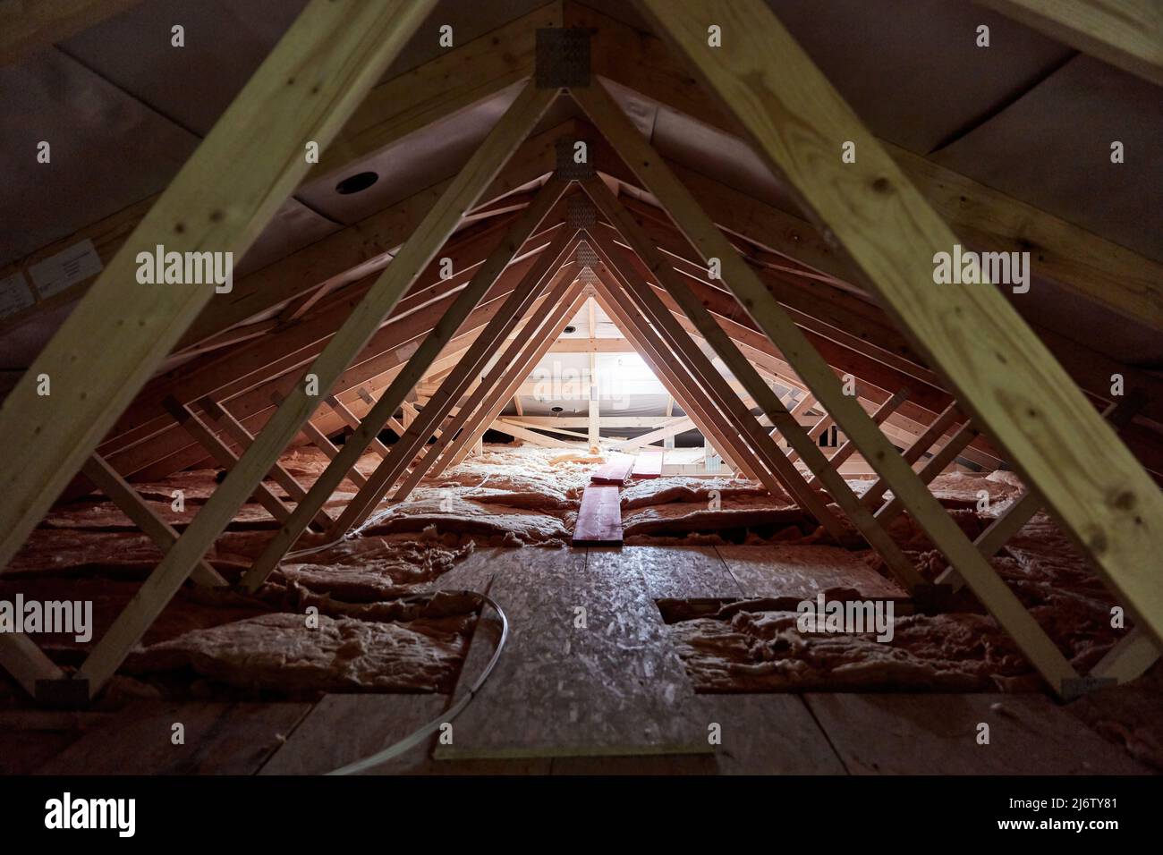 Dark attic with a small window and wooden beams in a new build house ...