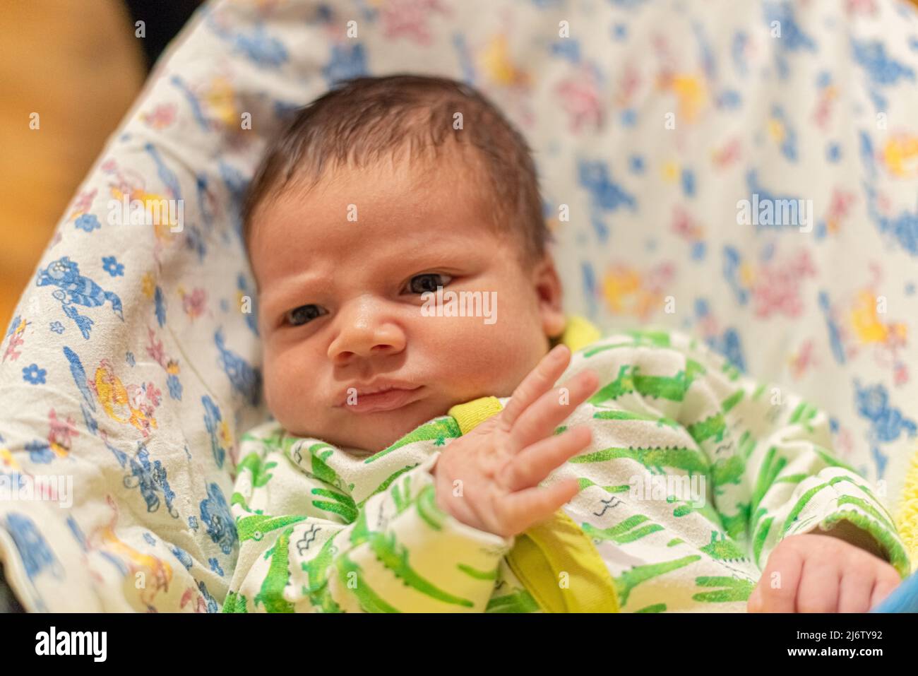 Newborn baby lying in bed with raised arms Stock Photo - Alamy