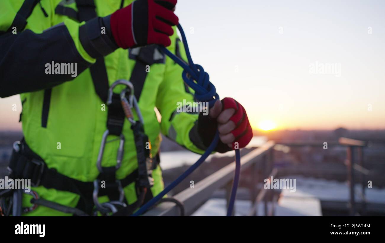 Industrial climber in green outfit ties node with loop attaching ...