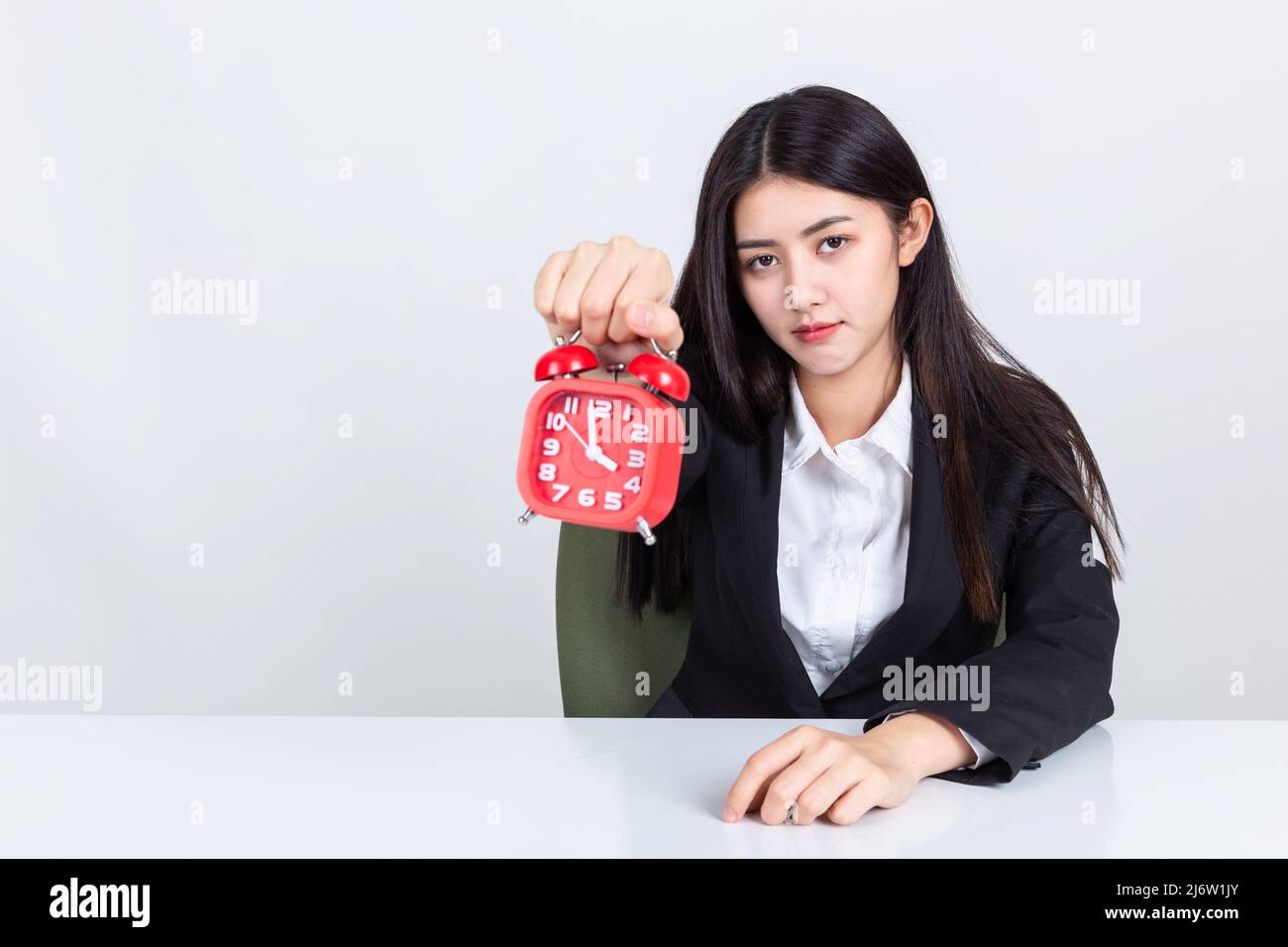 Asian business woman sit at desk in office holding alarm clock Stock ...