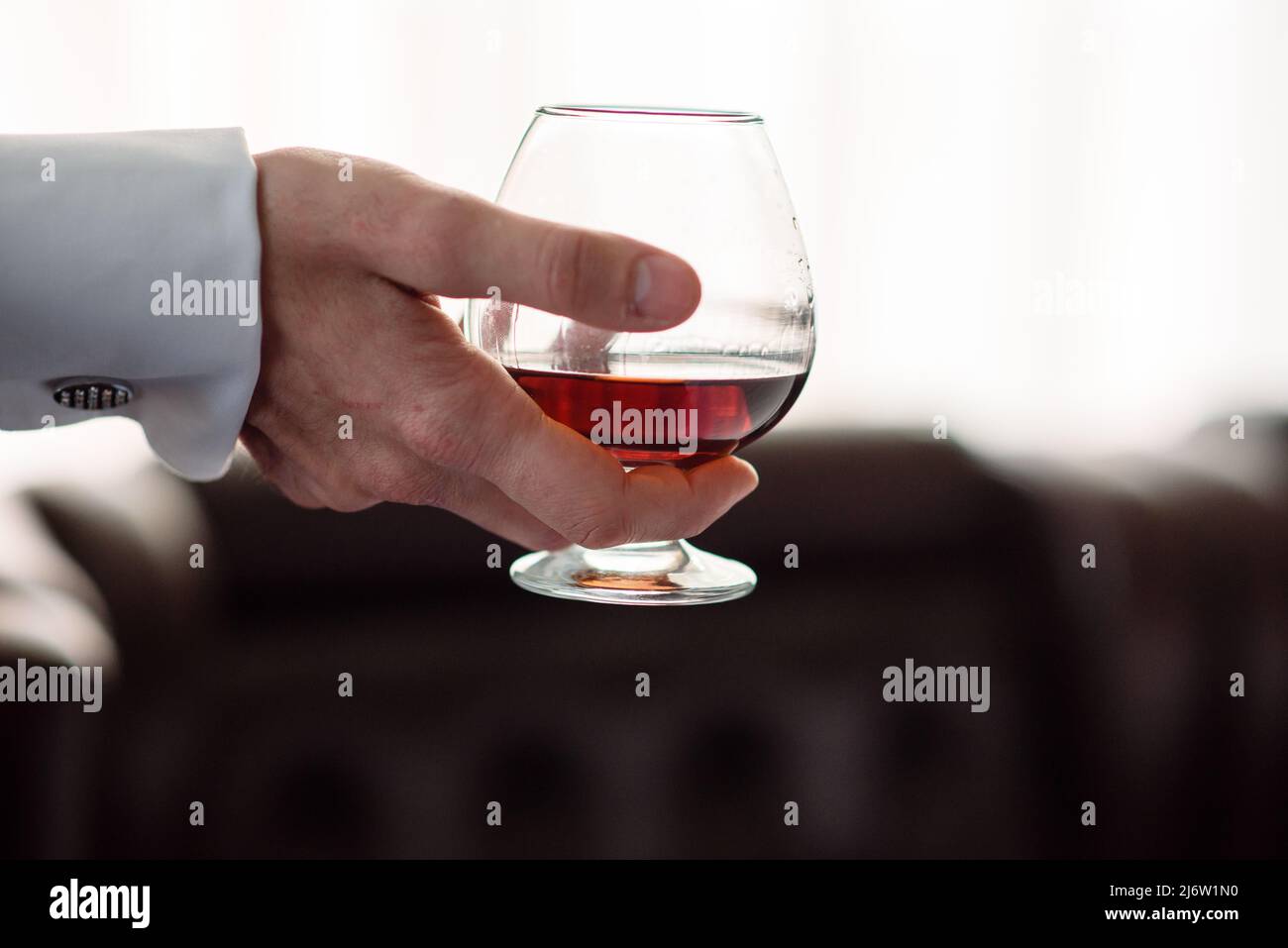 Hand with a glass of cognac Stock Photo - Alamy