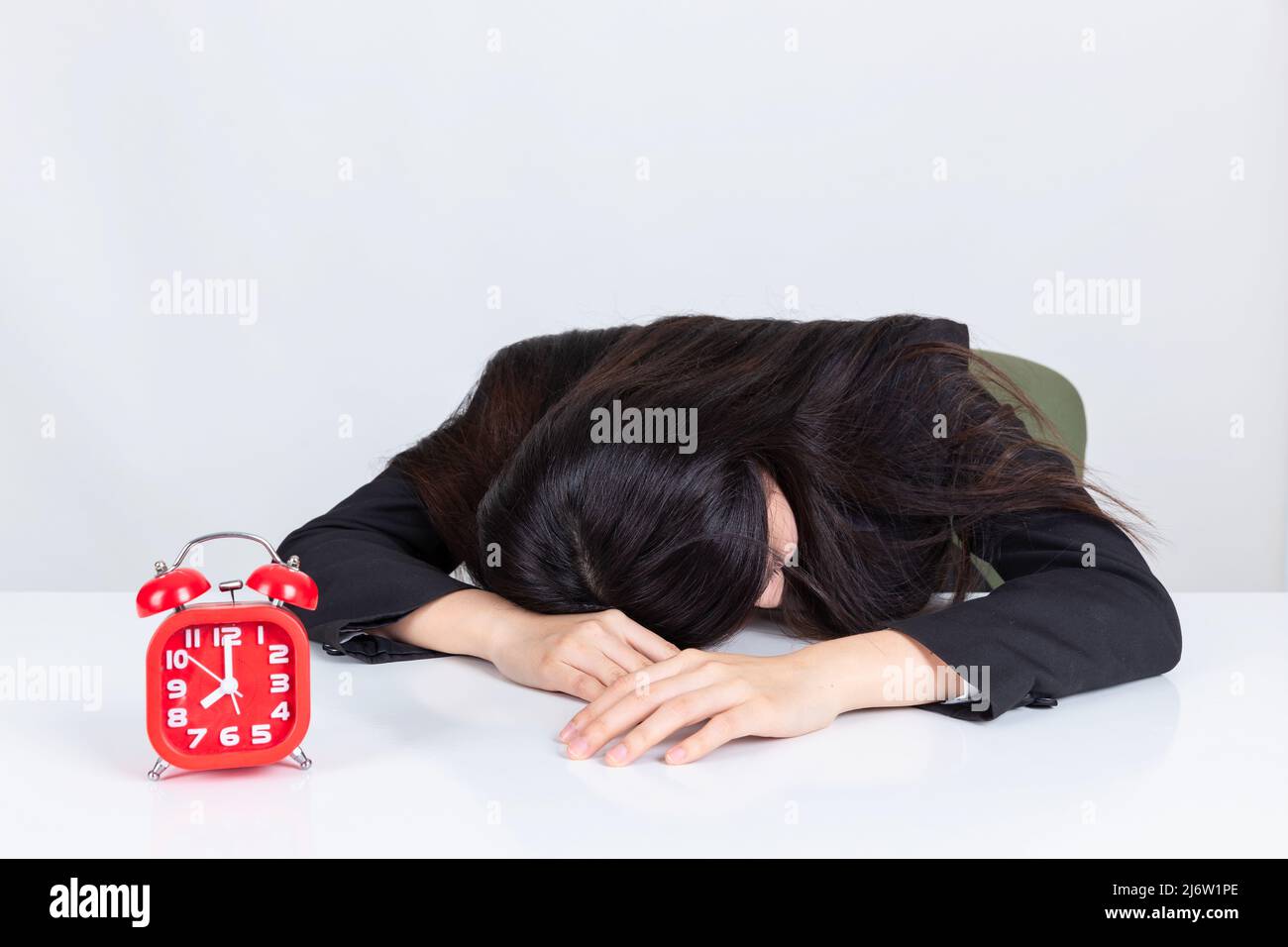Asian business woman sit at desk in office holding alarm clock Stock ...