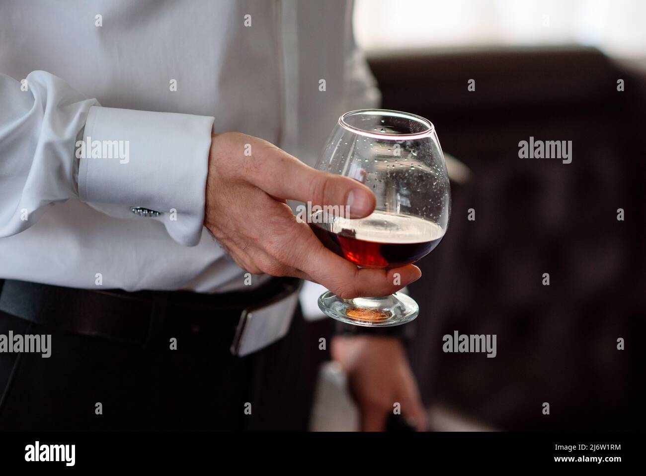 Hand, a glass of cognac Stock Photo - Alamy