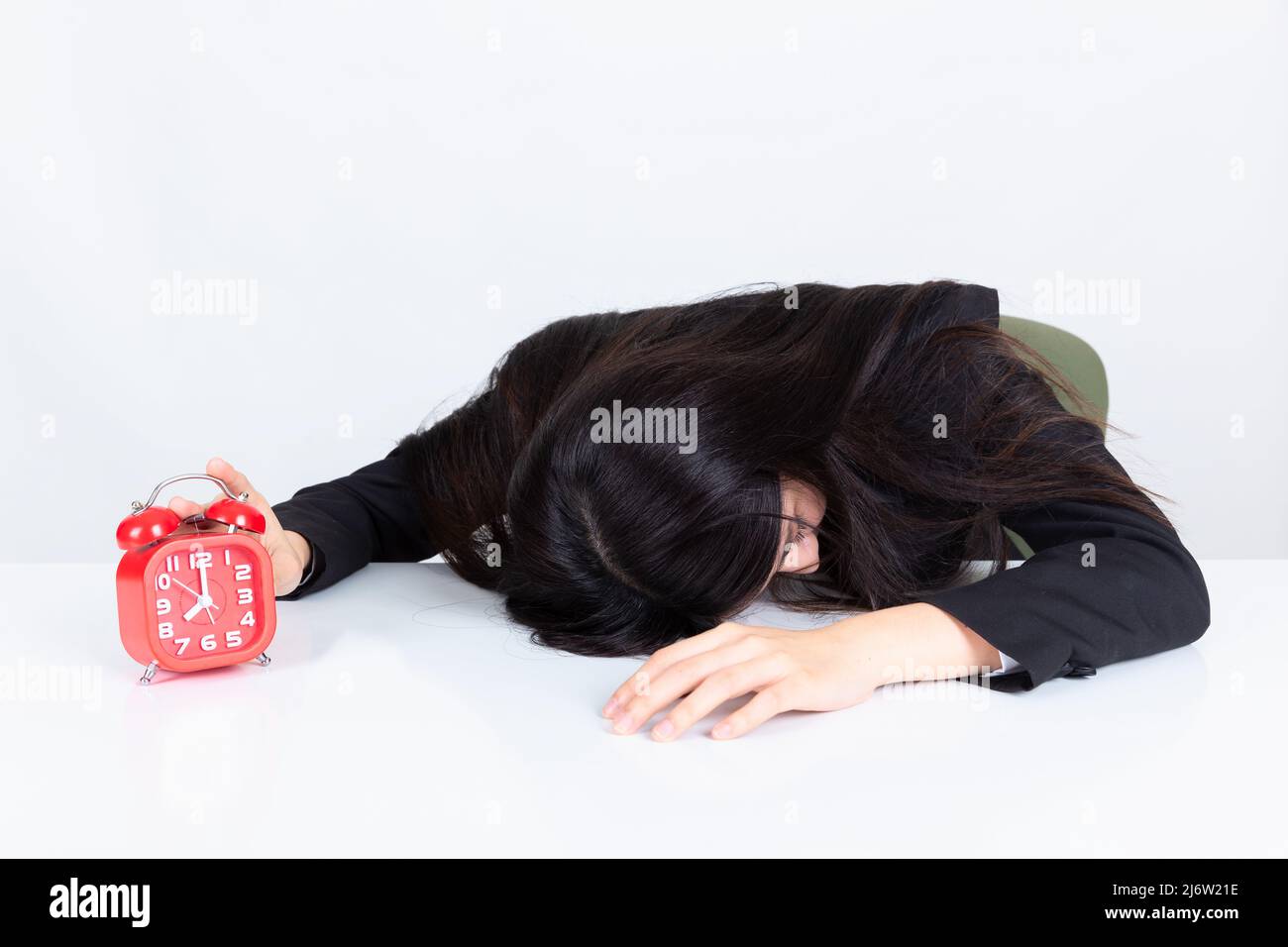 Asian business woman sit at desk in office holding alarm clock Stock ...