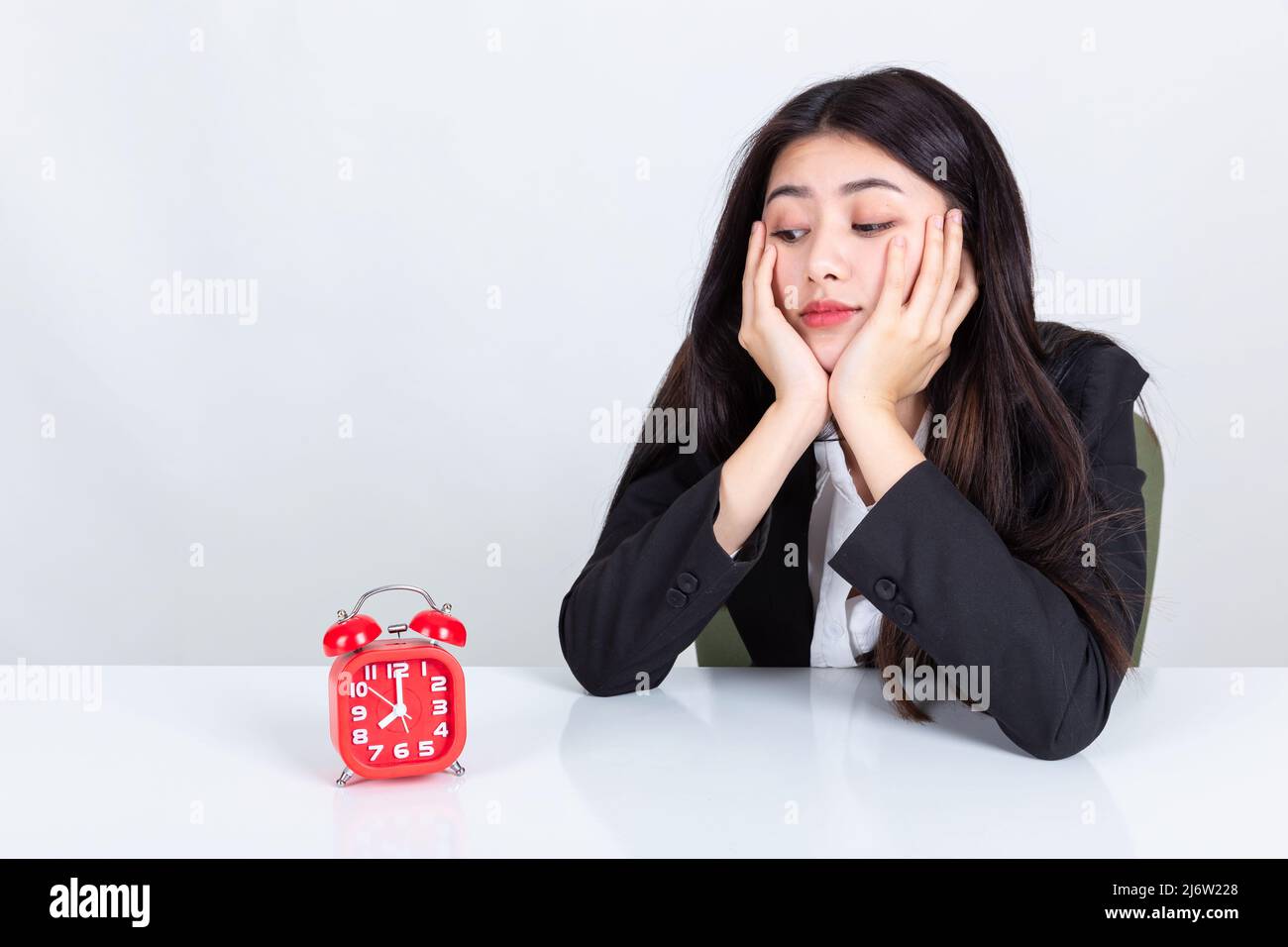 Asian business woman sit at desk in office holding alarm clock Stock ...