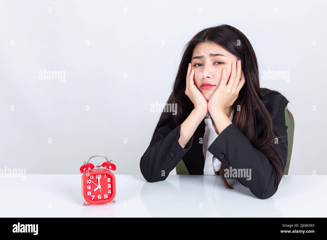 Asian business woman sit at desk in office holding alarm clock Stock ...