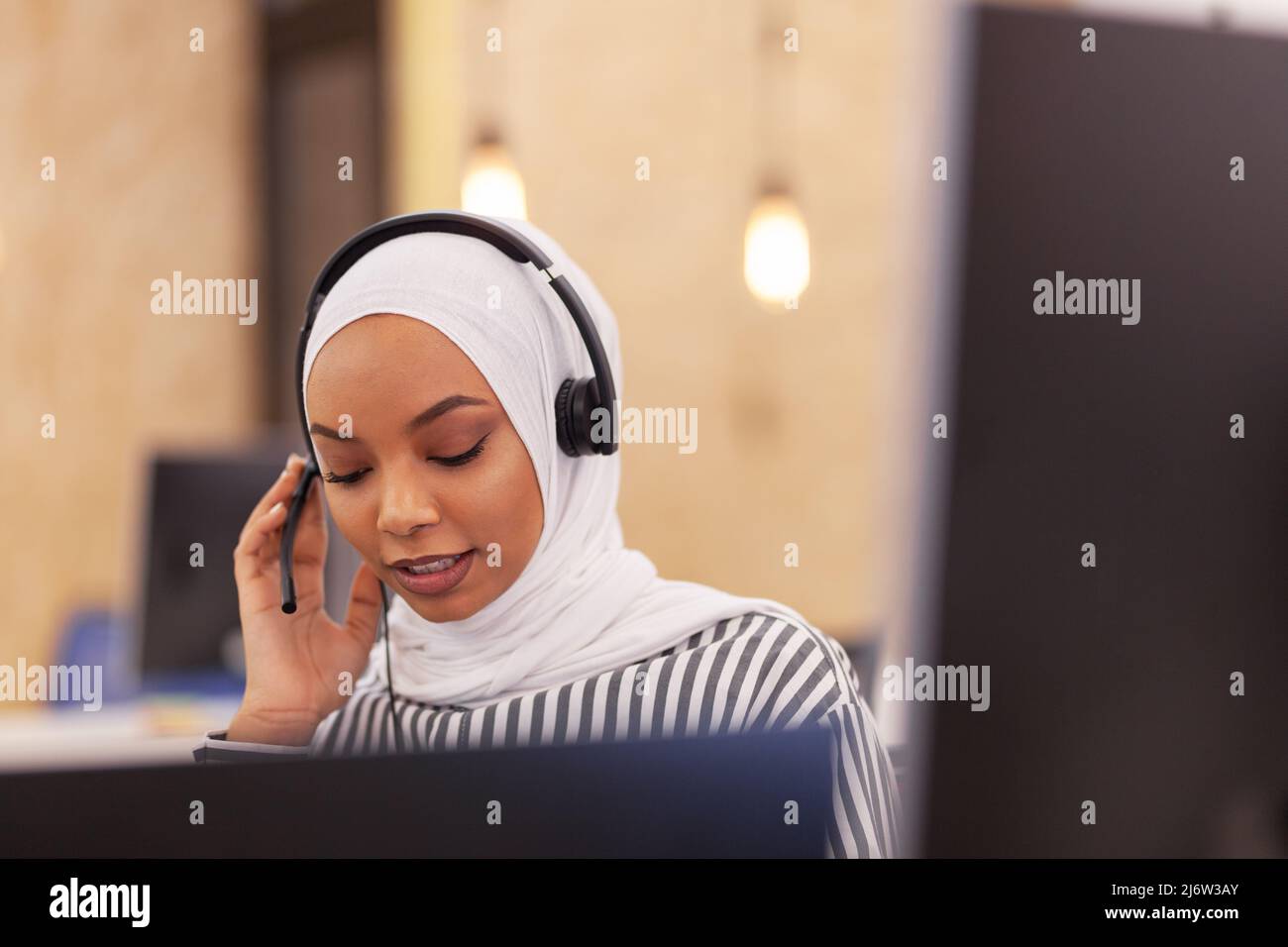 African american muslim girl with hijab and headset in a modern office ...