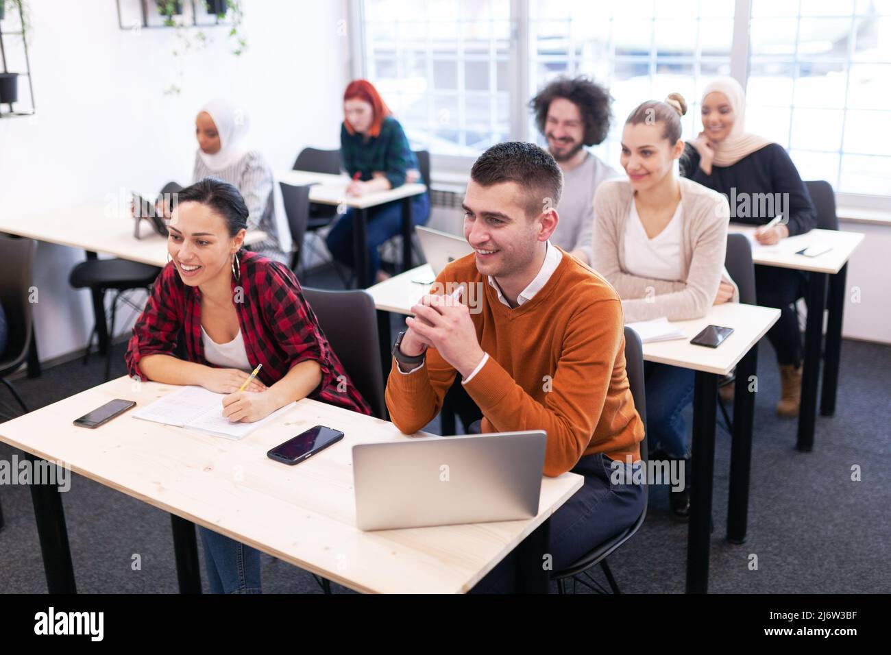 Multi ethnic students listening to a lecturer in a classroom. Smart ...