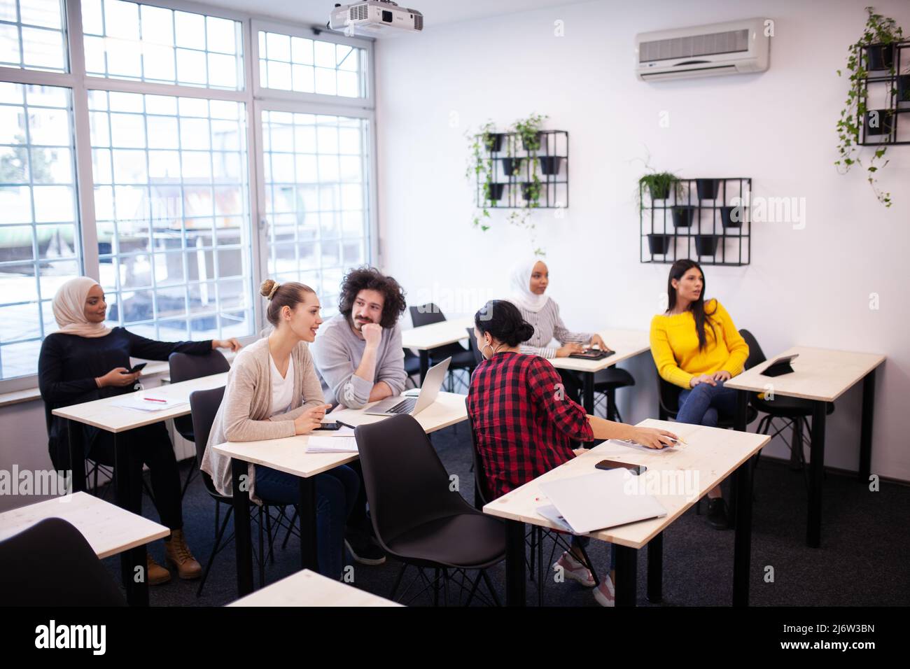 Multi ethnic students listening to a lecturer in a classroom. Smart ...