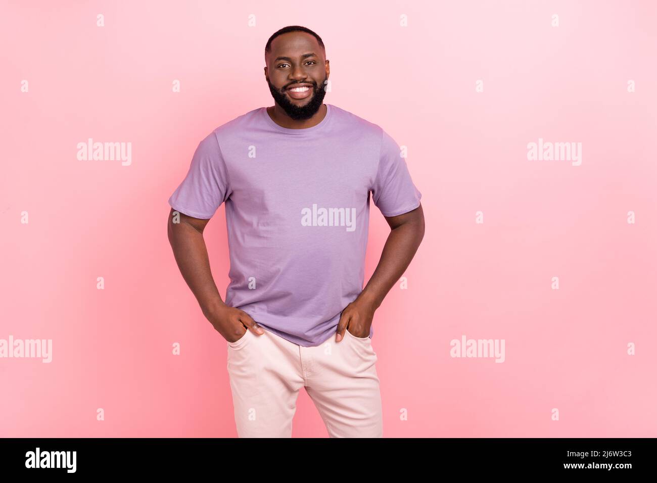 Portrait of attractive cheerful masculine guy holding hands in pockets ...