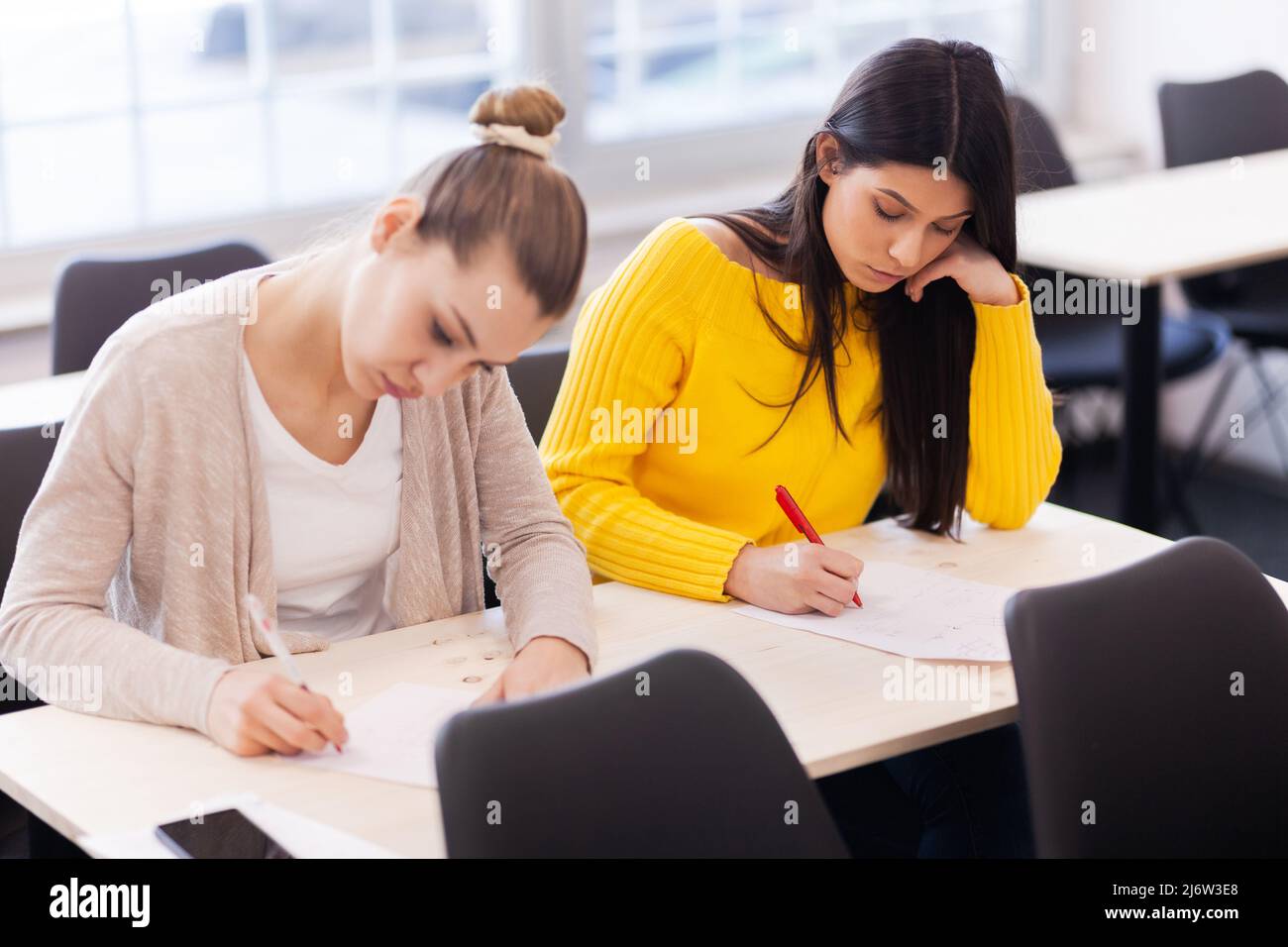 Students taking a test in a classroom. Smart young girls study at a ...