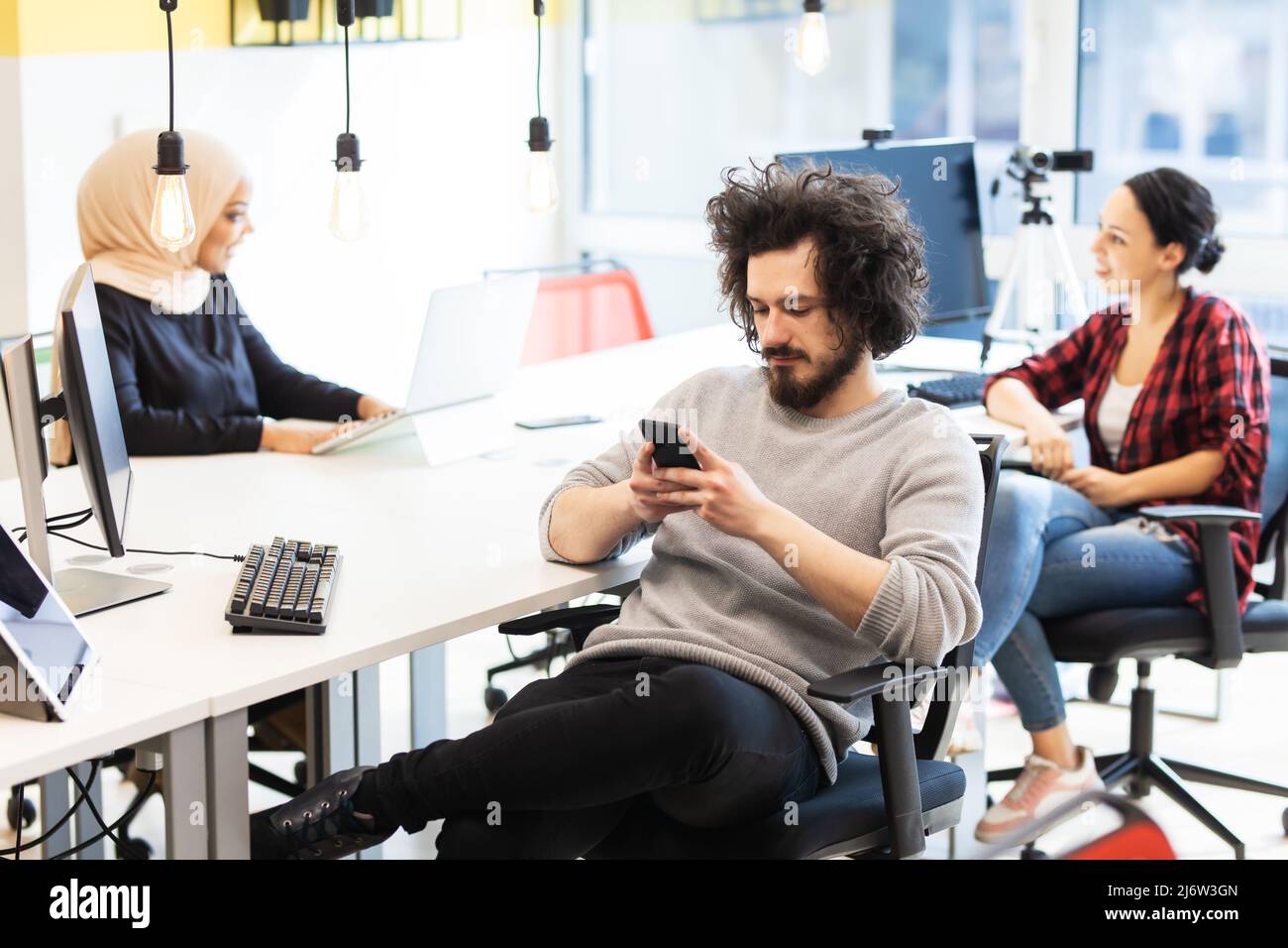 Creative team of young individuals working on desktop and laptop ...