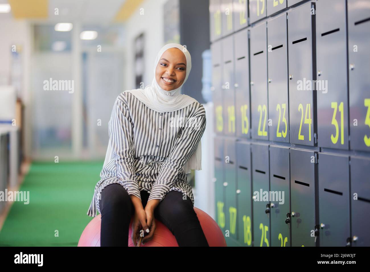 African american muslim girl with hijab sitting on balance ball n a ...
