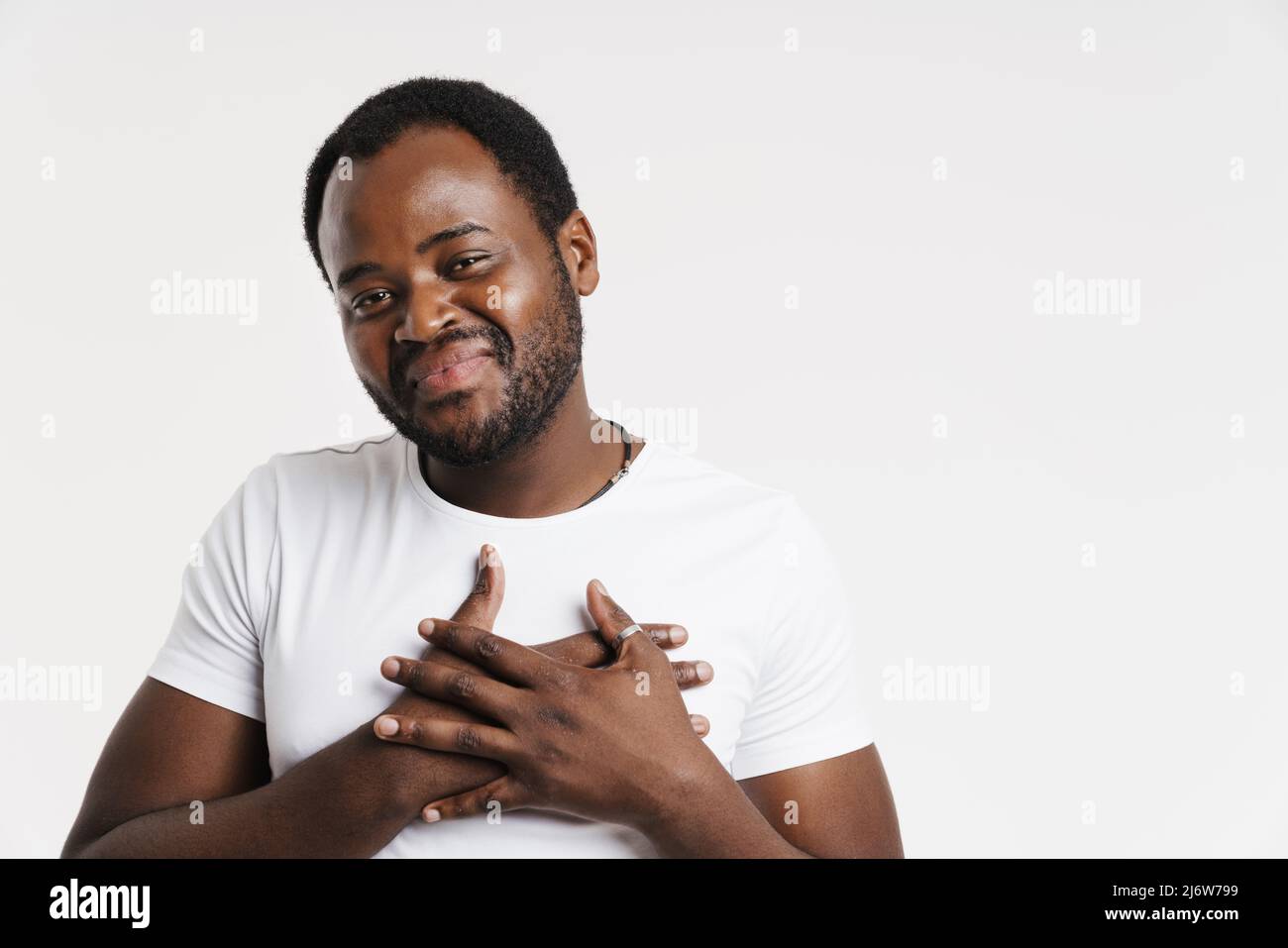 Black bristle man smiling while holding hands in his chest isolated ...
