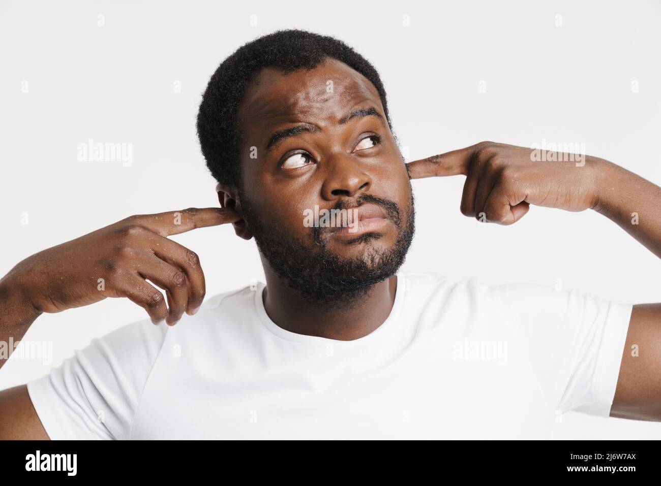 Black bristle man looking aside while plugging his ears isolated over ...