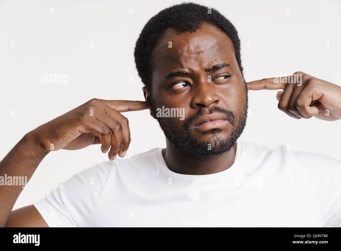 Black bristle man looking aside while plugging his ears isolated over ...