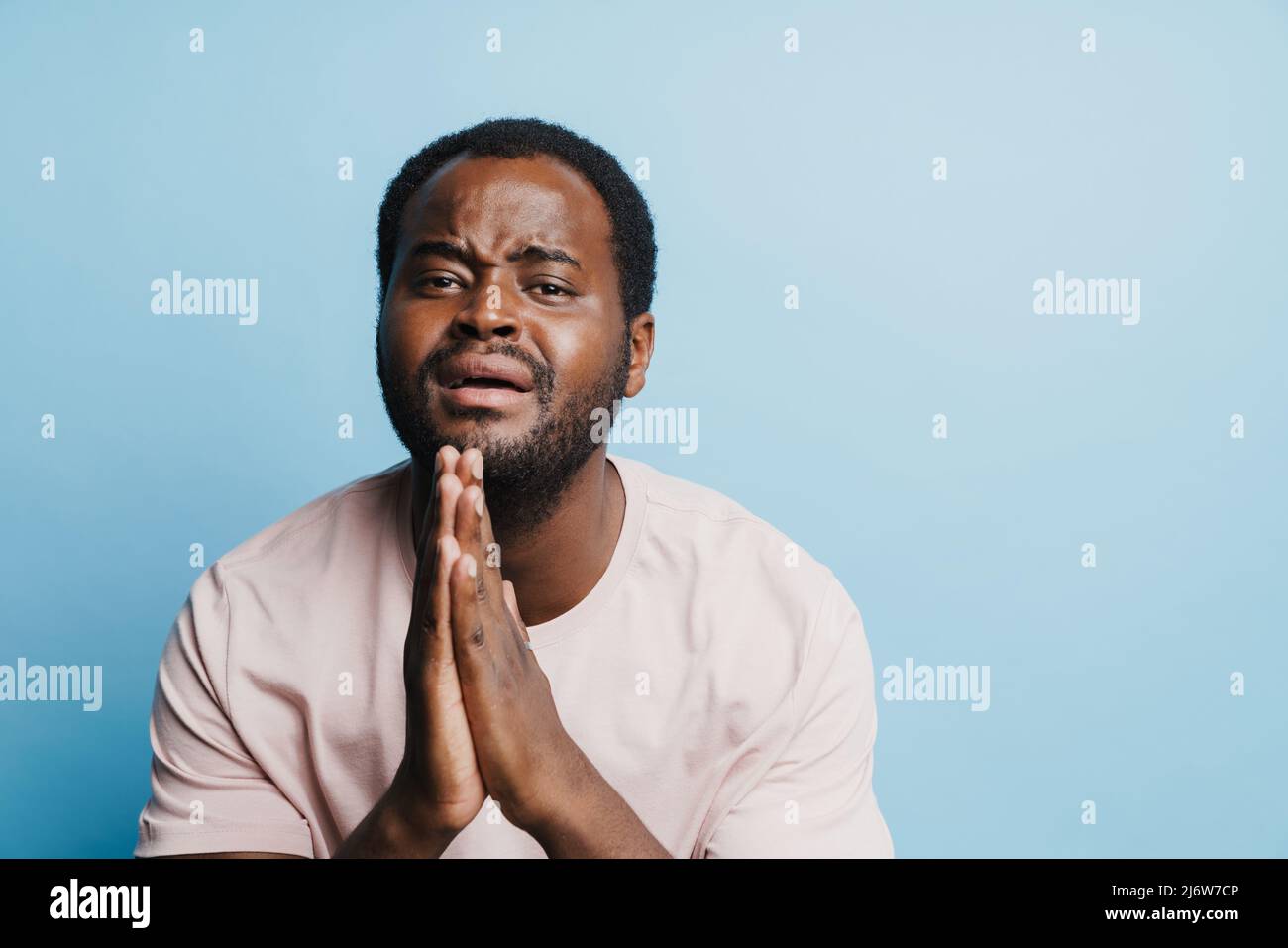 Black bristle man crying while holding his palms together isolated over ...