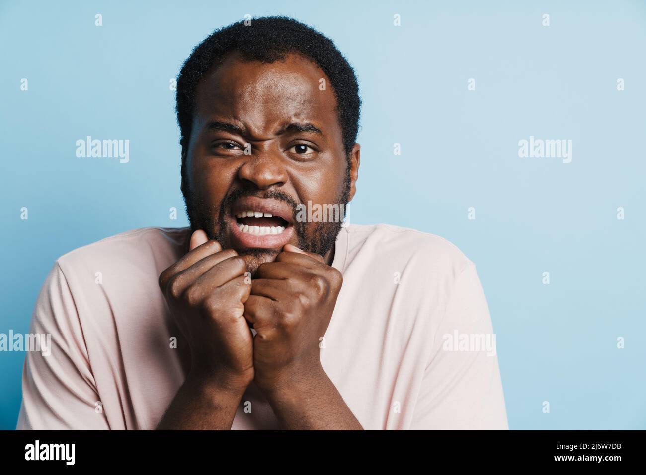 Black scared man grimacing while posing with clenched fists isolated ...